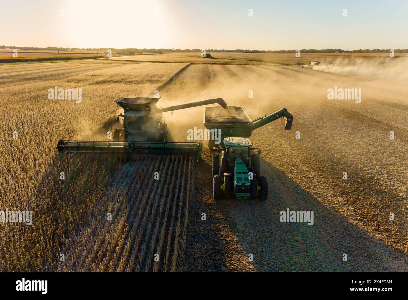 Aerial of combine harvesting soybeans and unloading into grain cart at ...