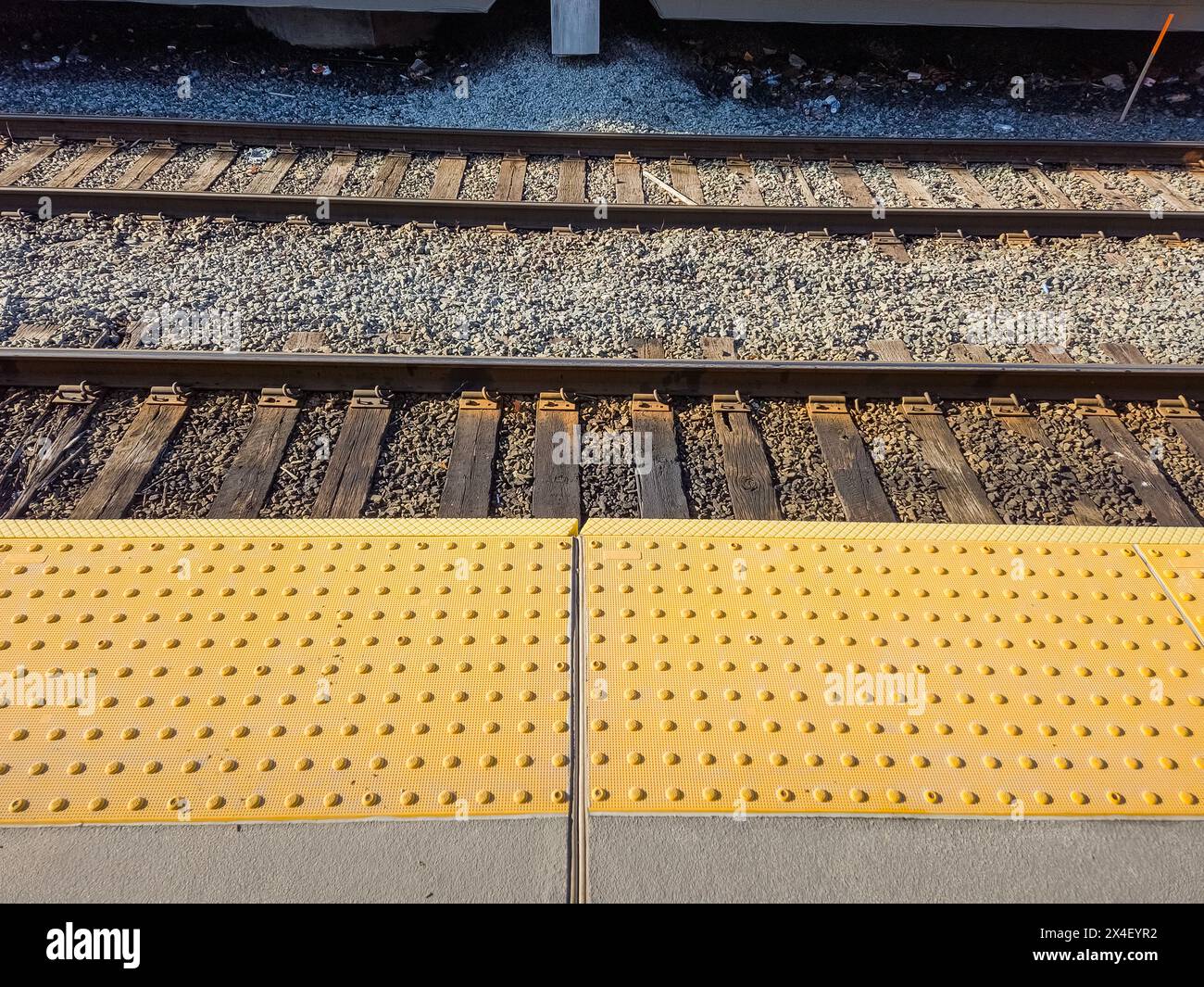 Yellow warning tile bumps in front of train tracks Stock Photo - Alamy
