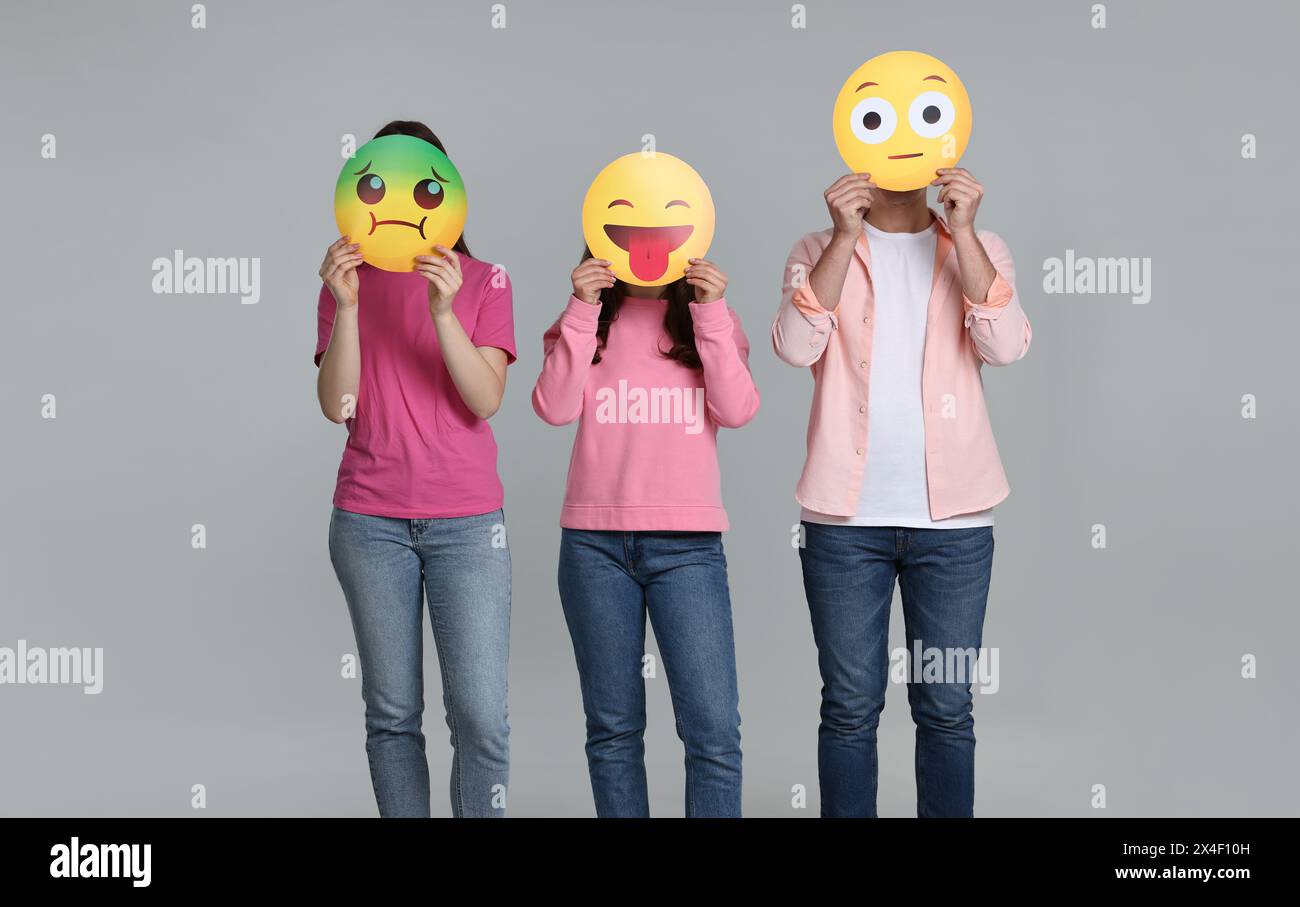 People covering faces with emoticons on grey background Stock Photo - Alamy