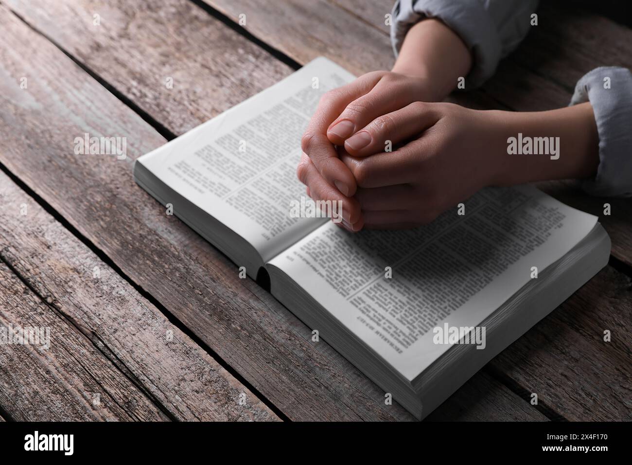 Religion. Christian woman praying over Bible at wooden table, closeup ...