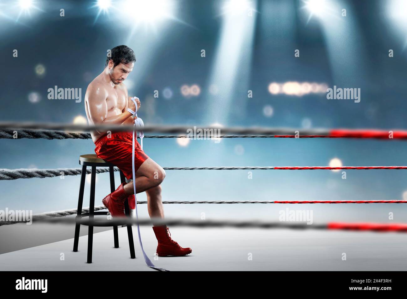 Portrait of a boxing man sitting and wrapping his hand with tape in the ...