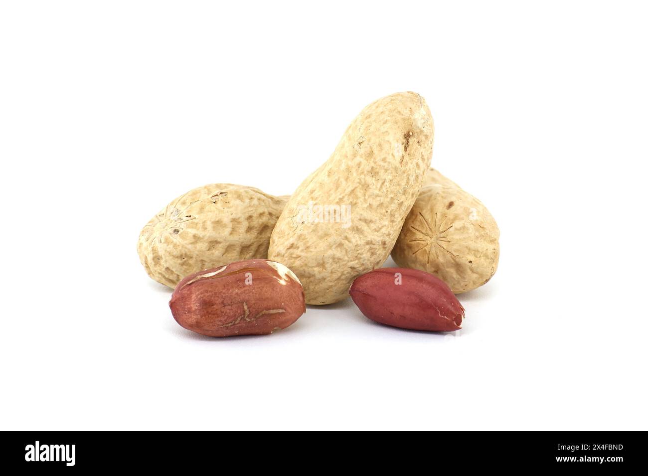 Pile of shelled and unshelled dried peanuts scattered on white ...