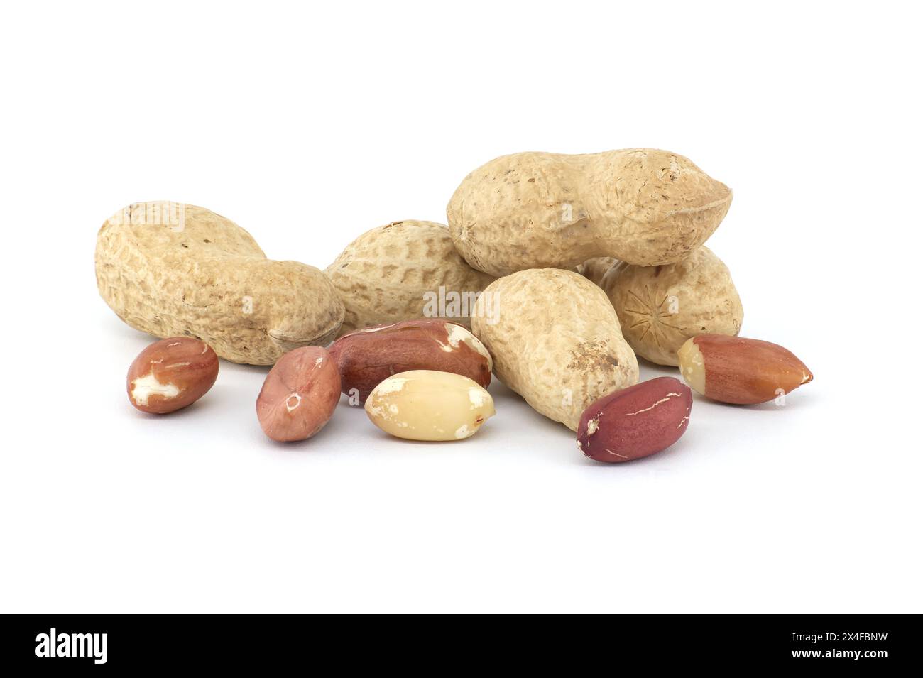 Pile of shelled and unshelled dried peanuts scattered on white ...