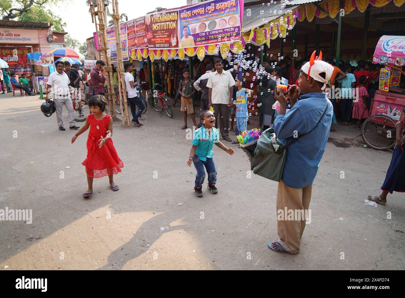 Joyful children dance while a street vendor blows soap bubbles. Bainan ...