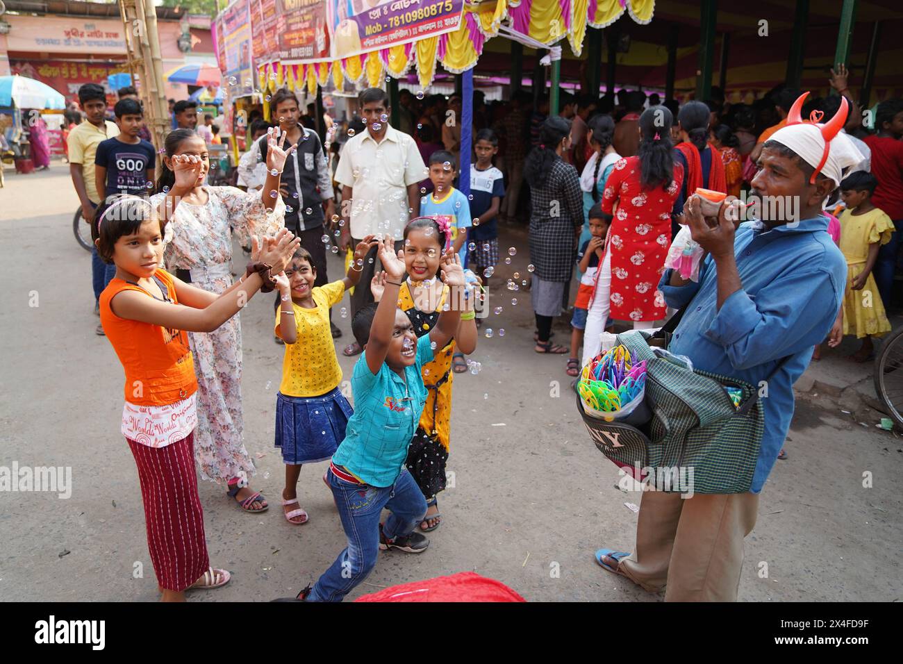 Joyful children dance while a street vendor blows soap bubbles. Bainan ...
