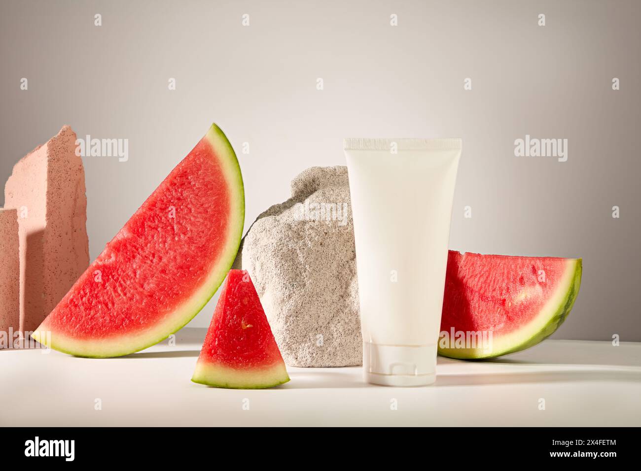Front view of cosmetic tube displayed with fresh watermelon slices and ...