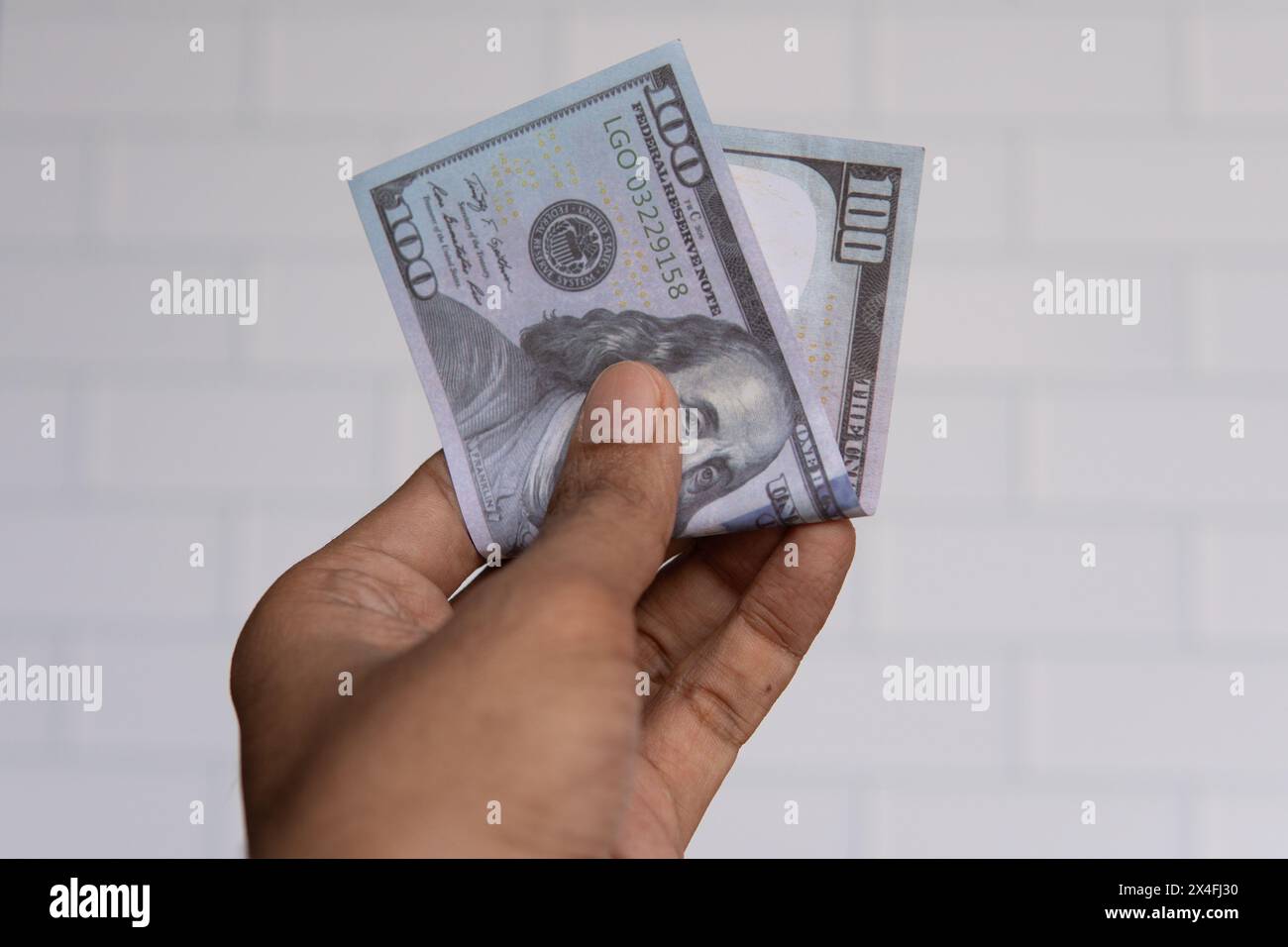 Closeup image of hand holding 100 US dollar banknotes against white ...