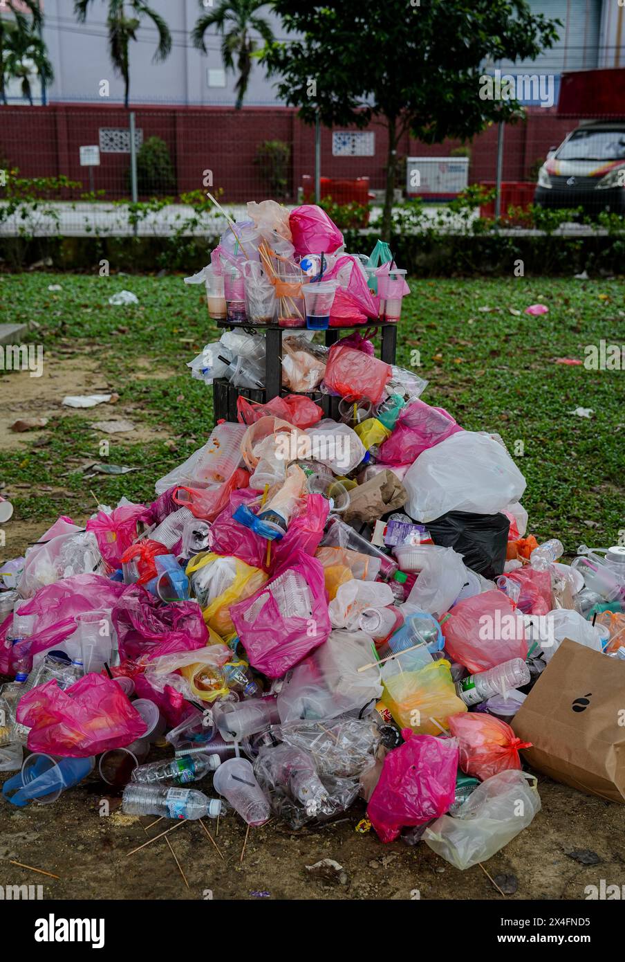 An overflowing public garbage bin surrounded by a mass of colorful ...