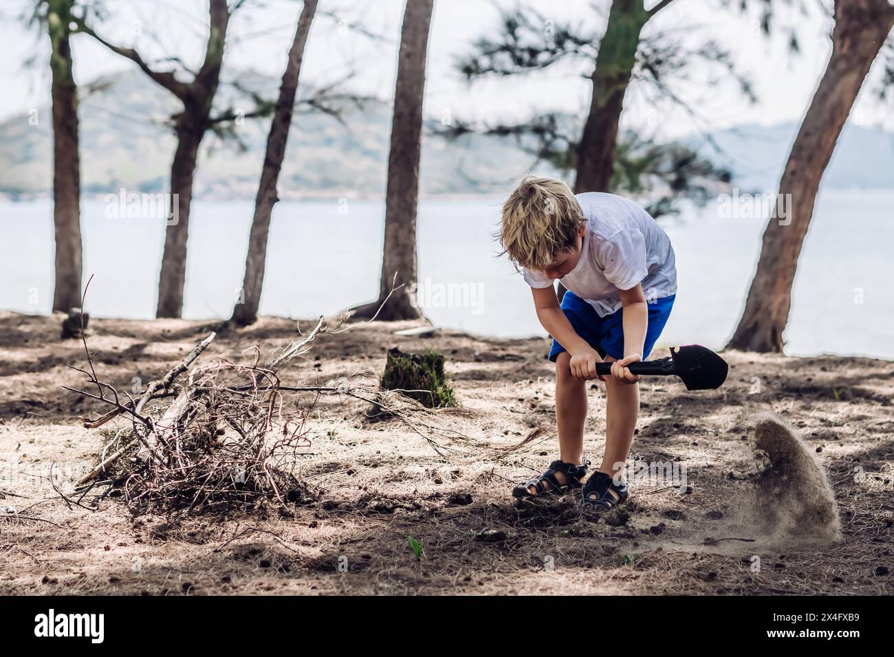 Cute boy digging soil in forest near sea beach. Family natural ...