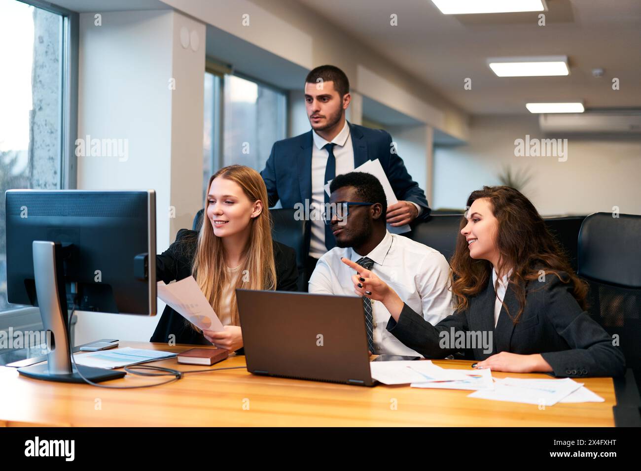 Multiethnic team works in modern office, young woman points at computer ...