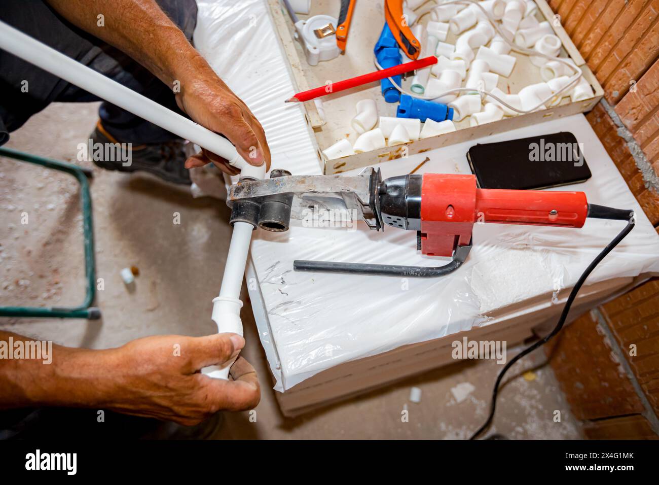 Plumber's hands as using handy power tool, iron for soldering, welding ...