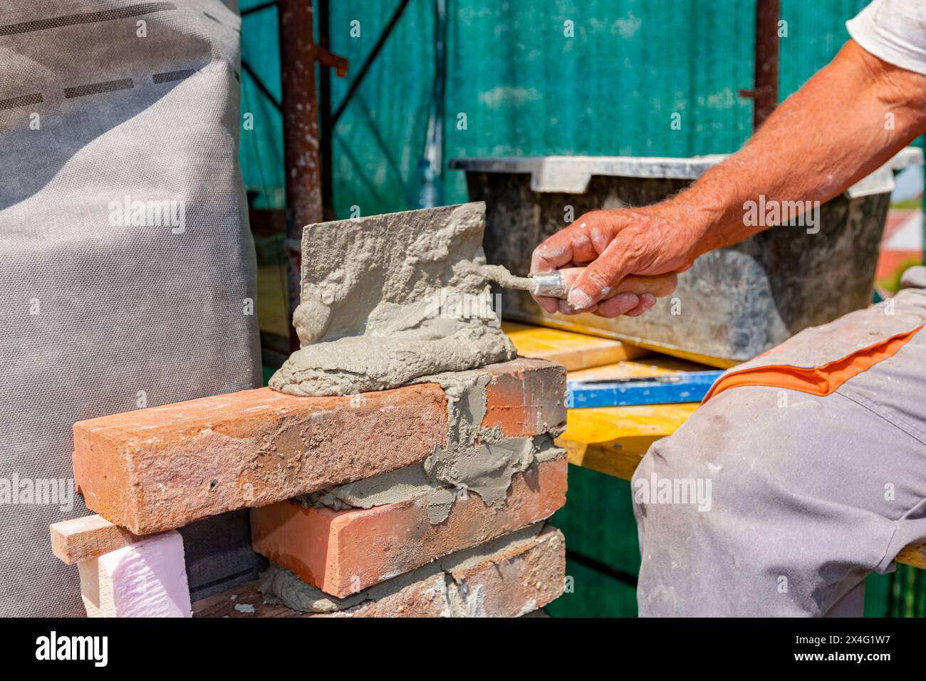 Mason, bricklayer worker is using brick to mount a corner, facade of ...