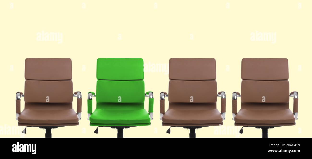 Vacant position. Green office chair among brown ones on beige ...