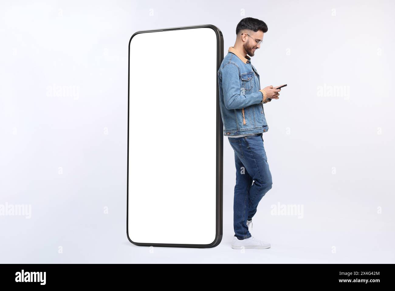 Man with mobile phone standing near huge device with empty screen on ...