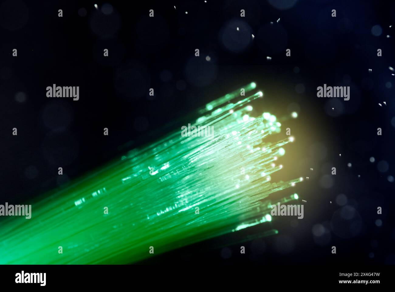Optical fiber strands transmitting light on black background, macro ...