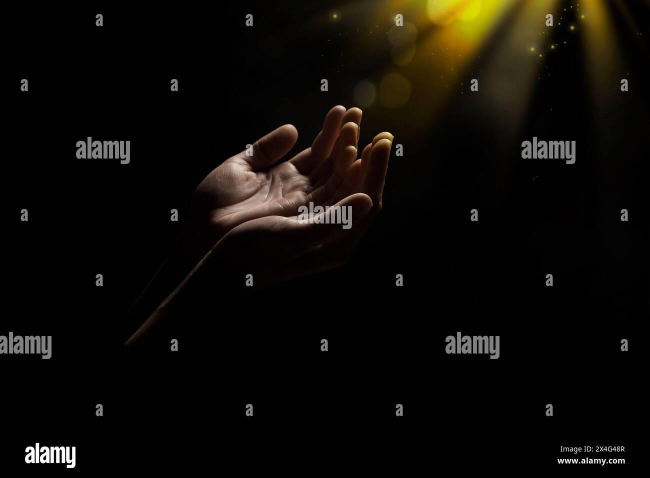 Christian woman stretching hands towards holy light in darkness ...