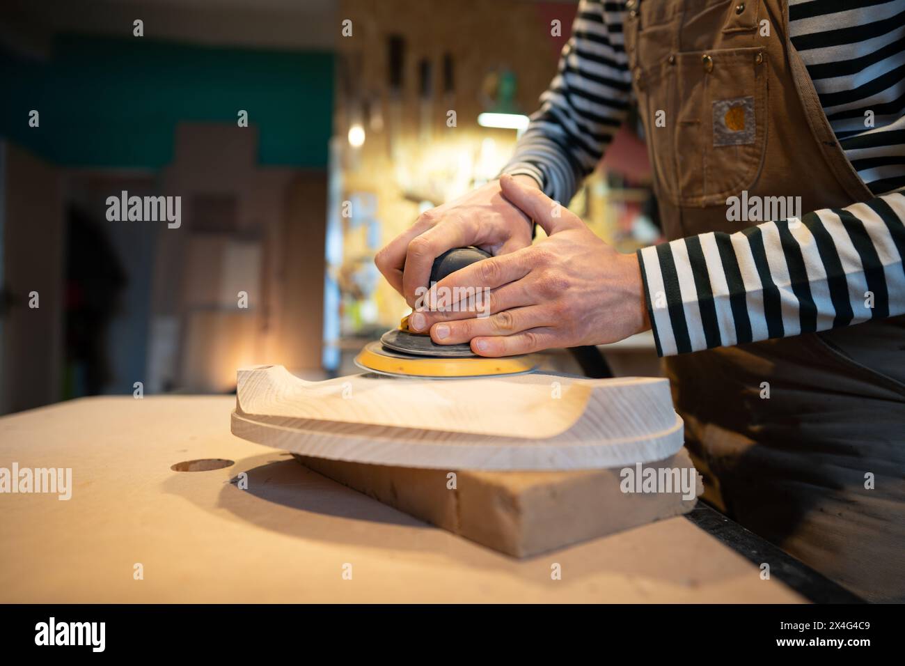 Closeup of sanding wood with orbital sander at workshop. Carpentry ...