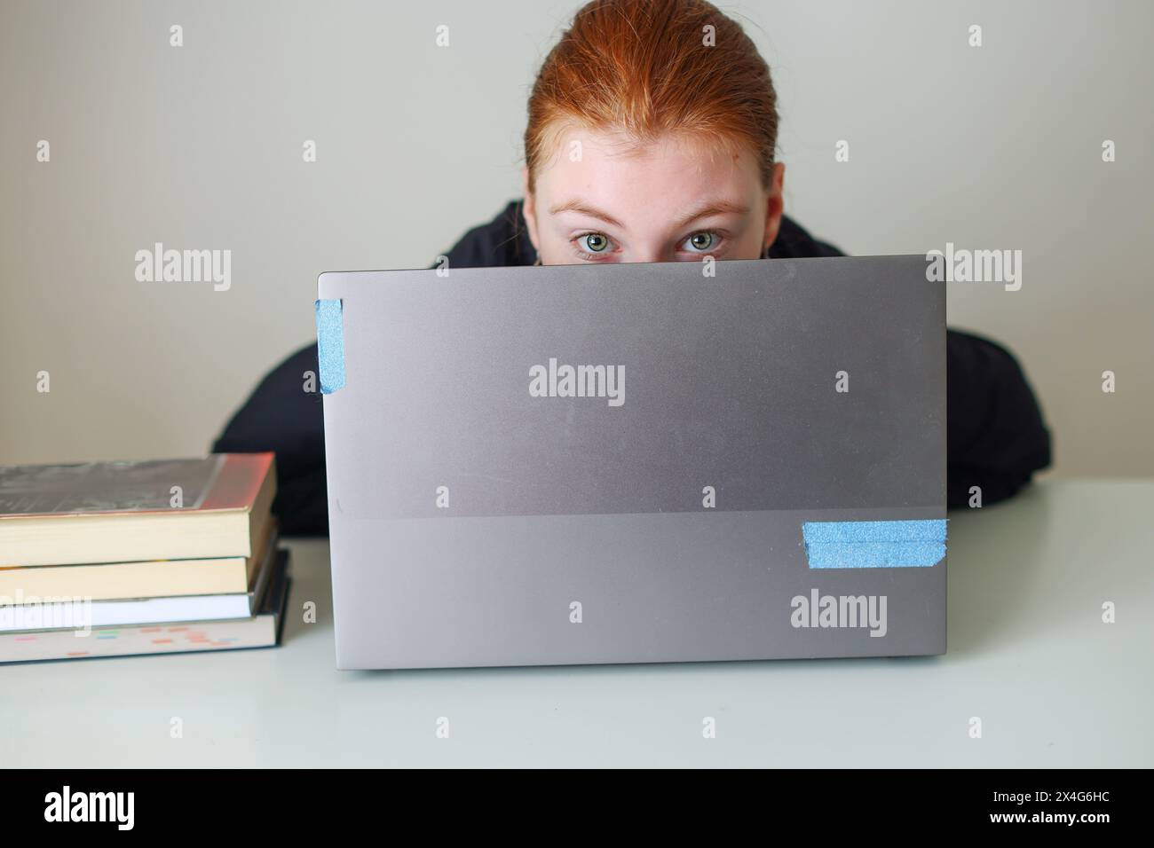 Young student girl sit at table with textbooks and laptop staring aside ...