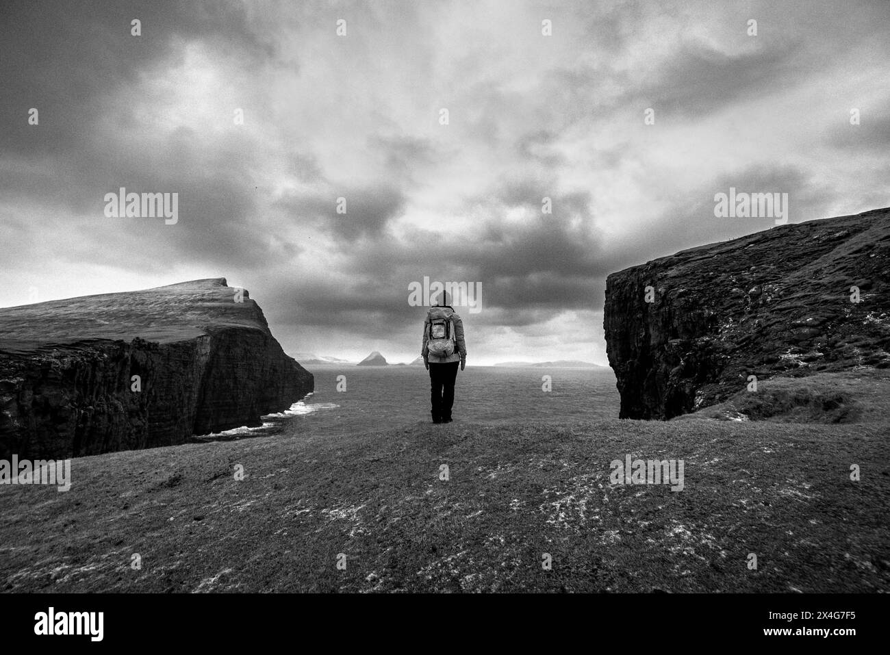 Person stands alone at edge of cliff by the ocean, Faroe Islands Stock ...