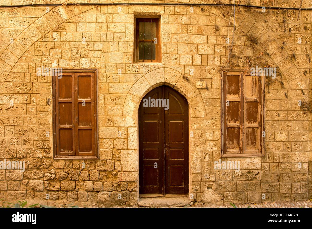 The facade of an ancient stone house with a wooden door on the ...