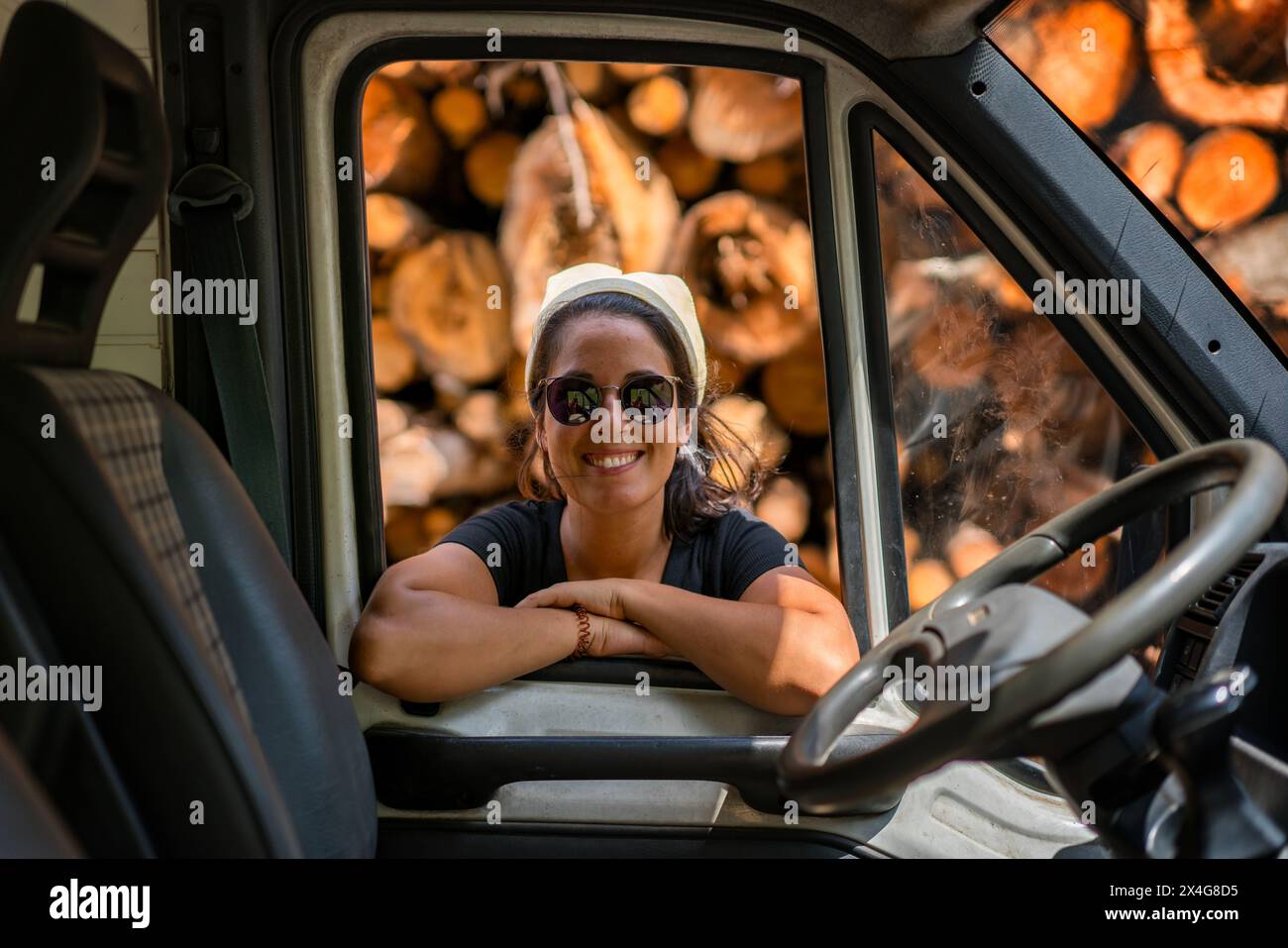 Woman looking through a car window with wood logs behind her Stock ...