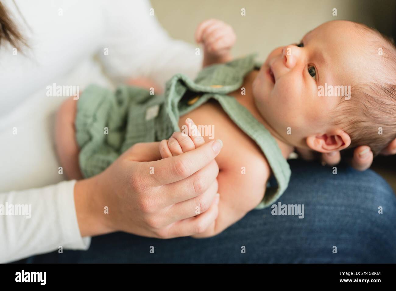 Mother's hand holding newborn baby boy's hand at home Stock Photo - Alamy