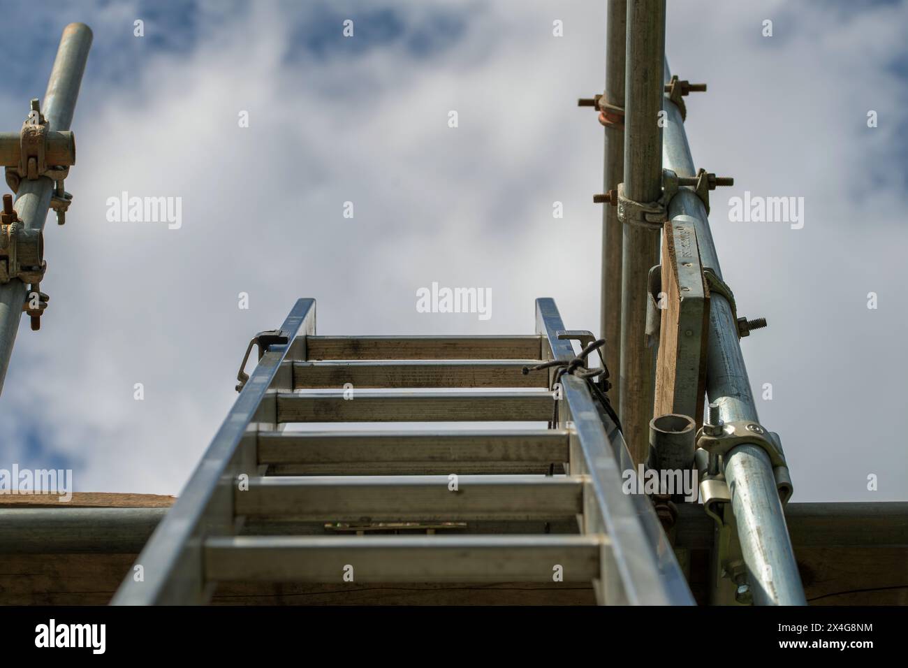 A view looking up a ladder into the sky leaning against scaffolding ...