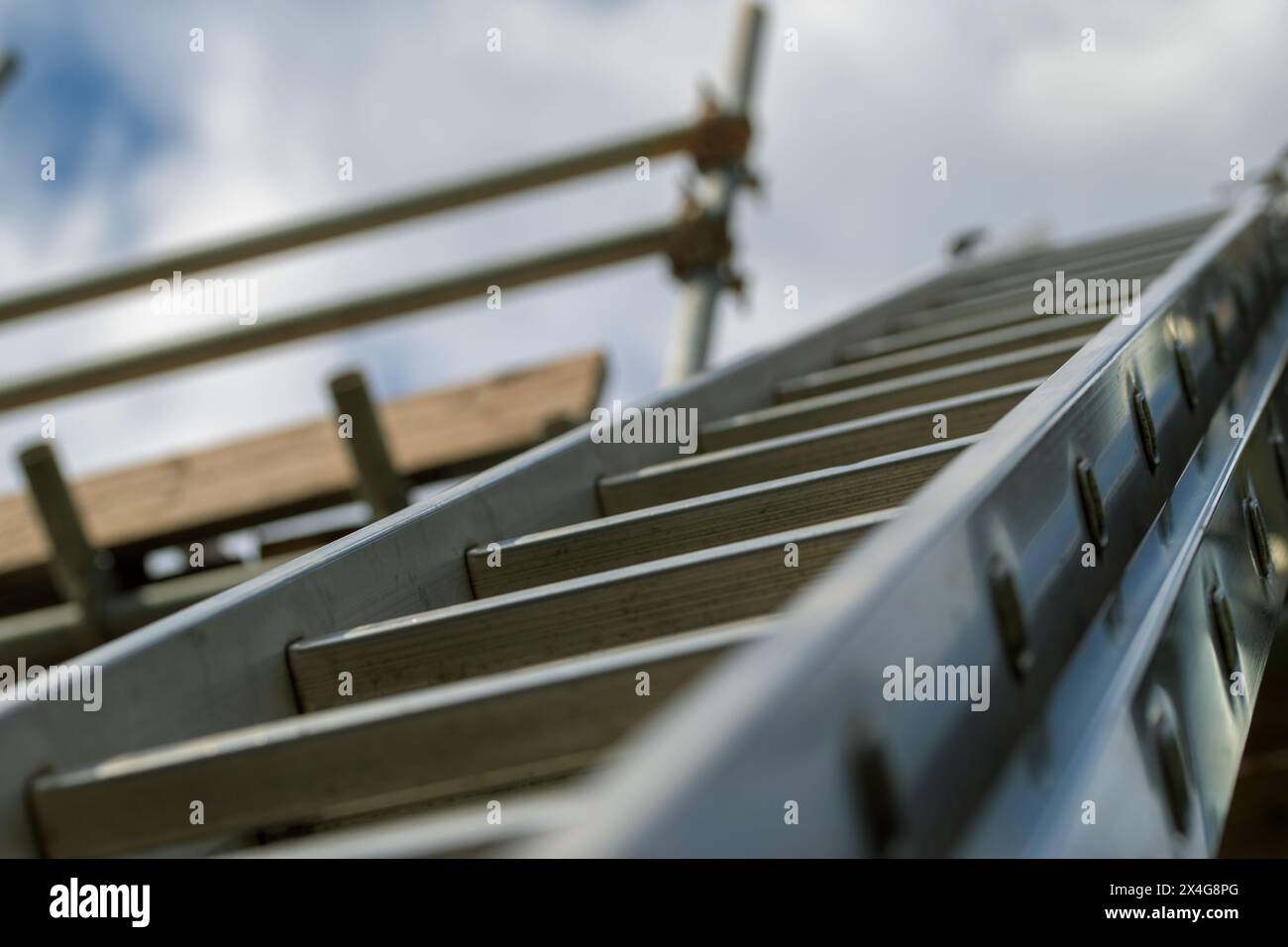 A view looking up a ladder into the sky leaning against scaffolding ...