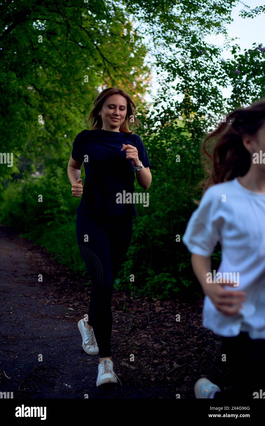 mother and daughter run together along a green alley Stock Photo - Alamy