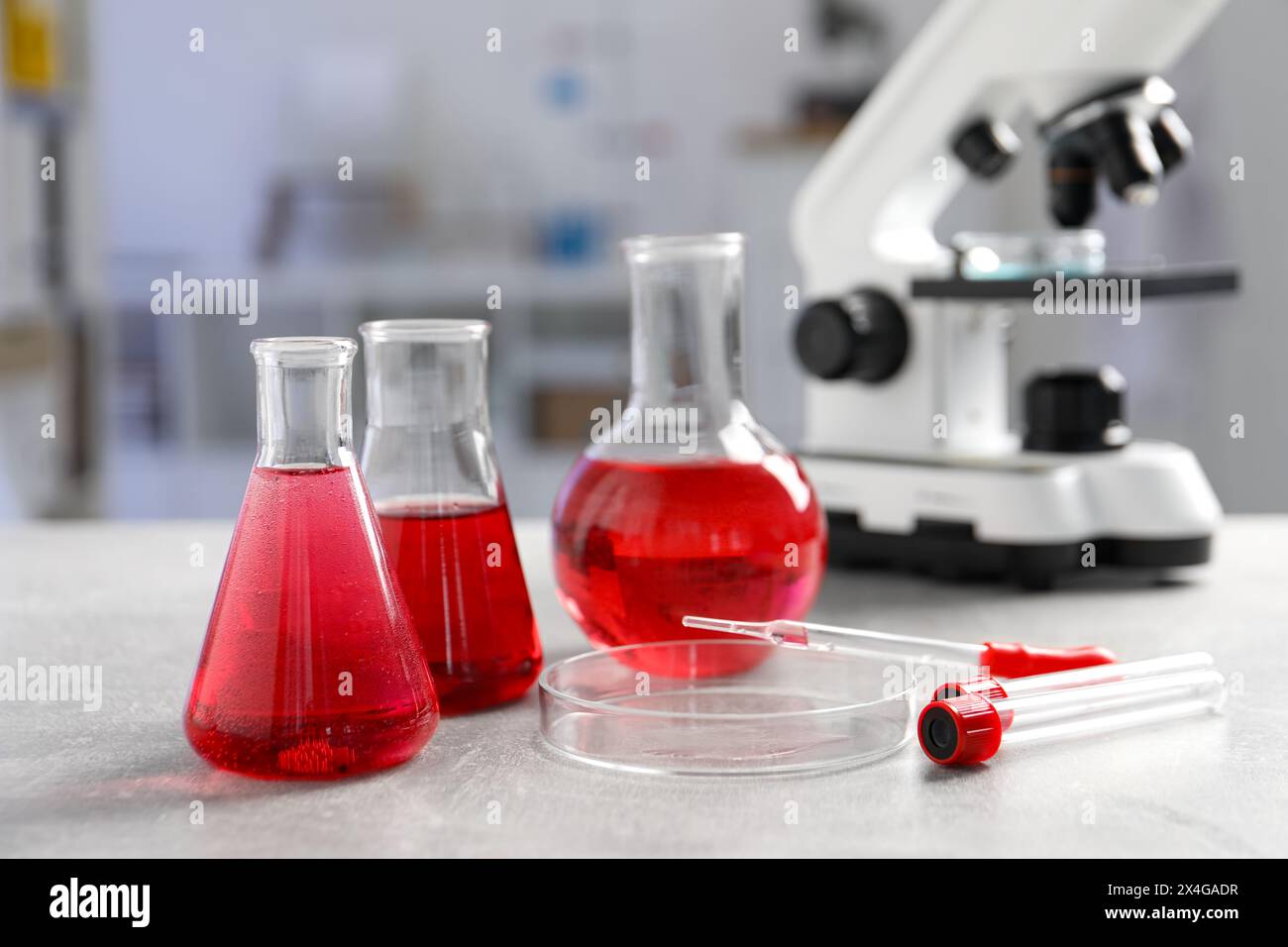 Laboratory analysis. Different flasks with red liquid and microscope on ...