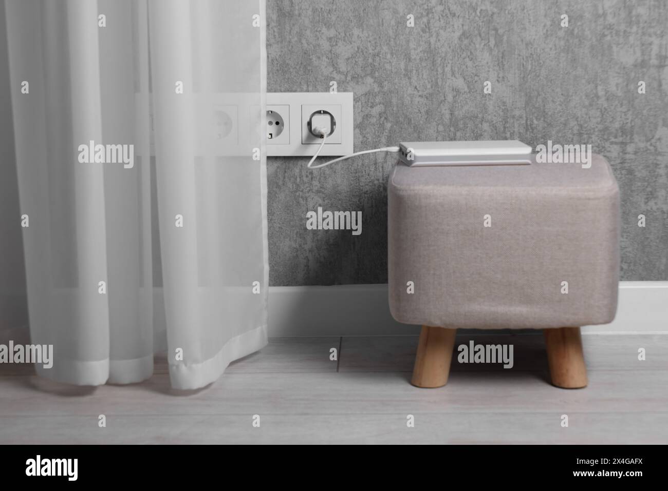 Power bank plugged into electric socket on grey wall Stock Photo - Alamy