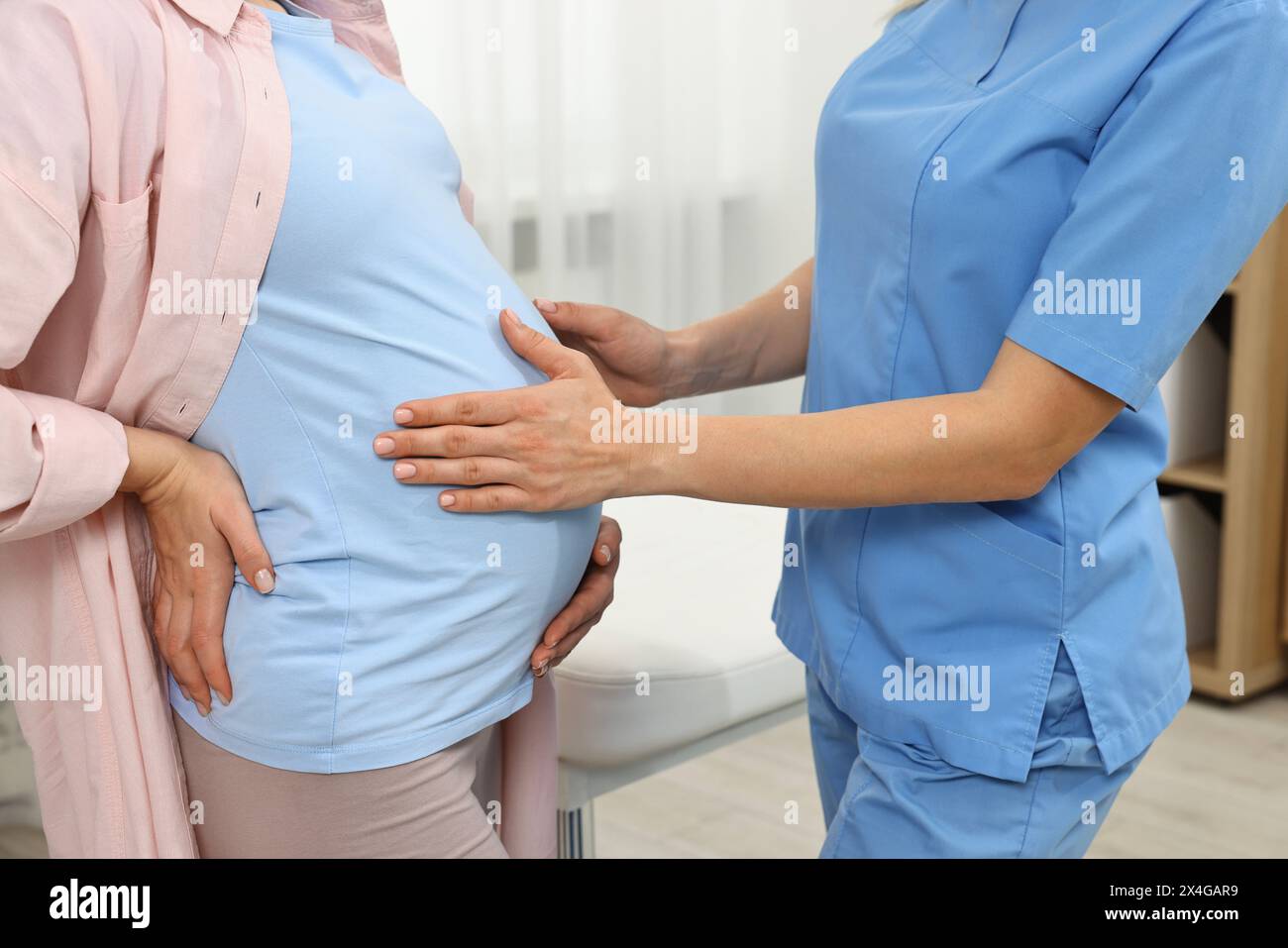 Pregnancy checkup. Doctor examining patient's tummy in clinic, closeup ...
