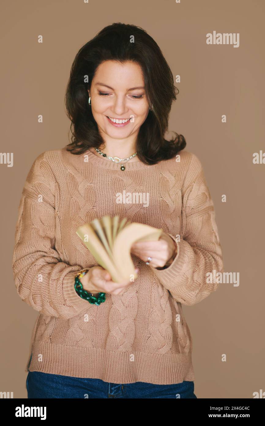 Studio portrait of beautiful 40 year old woman flips through pages of ...