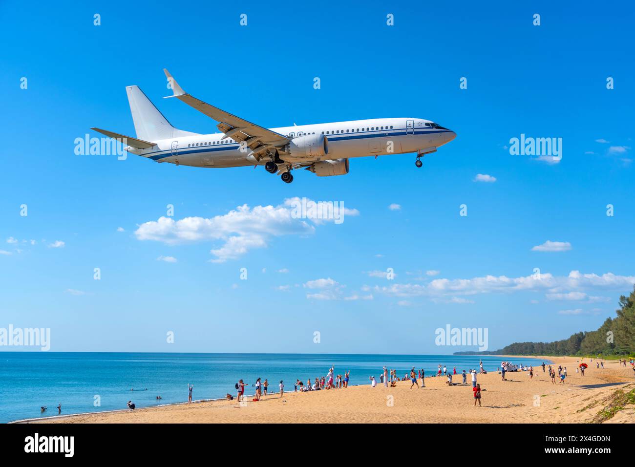 Airplane landing above beautiful beach with people on the beach and sea ...