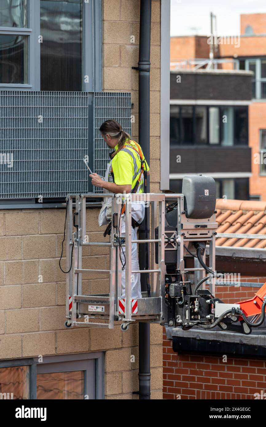 Construction worker in a high visibility vest uses a lift to inspect or ...