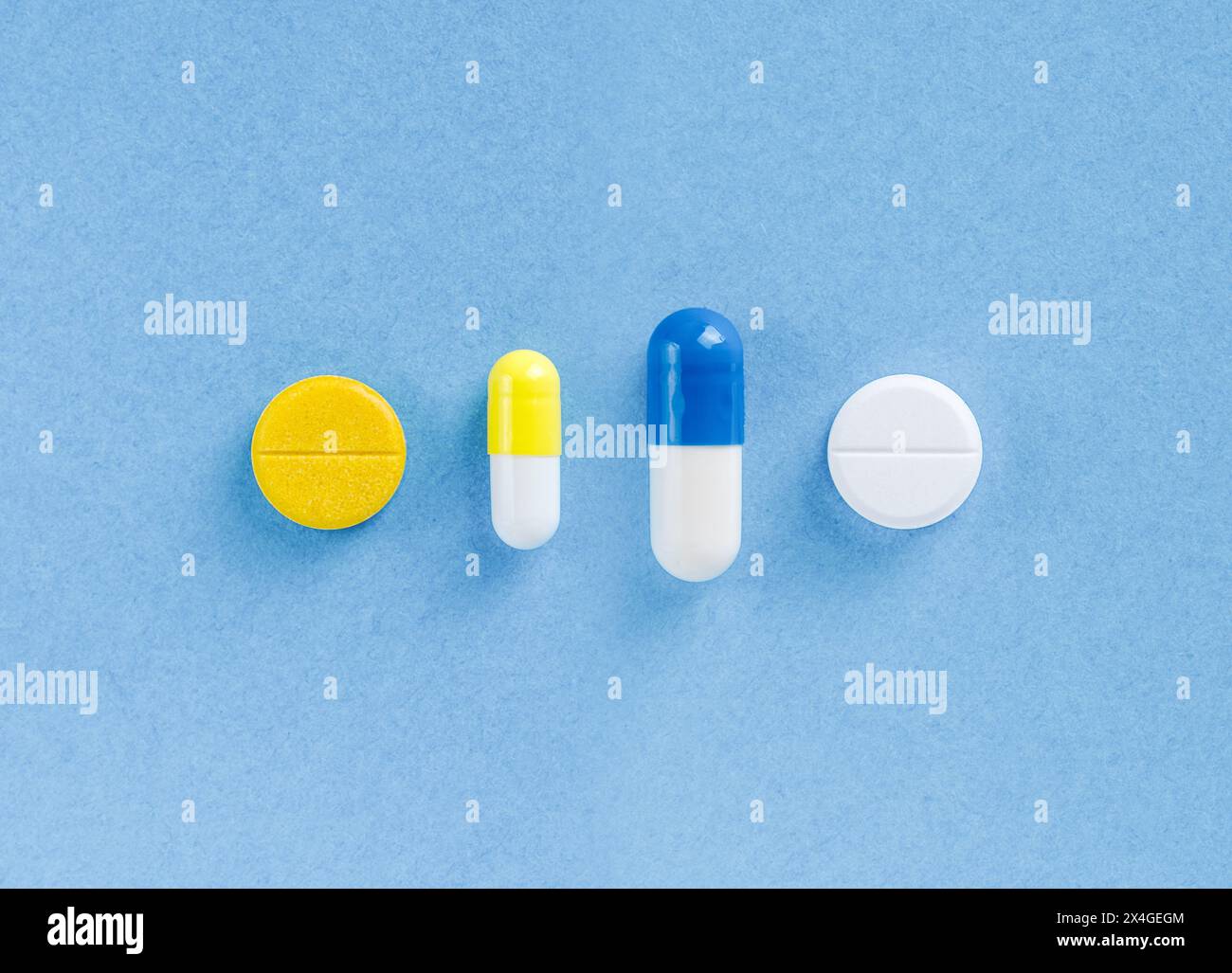 Medical capsules and pills in a line on light blue top view. Preventive ...