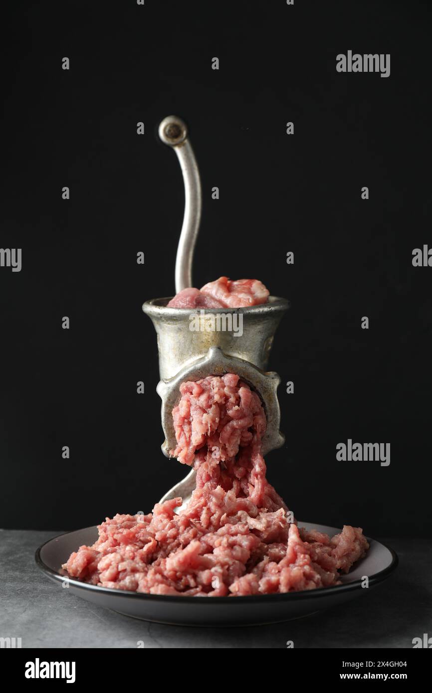 Manual meat grinder with beef mince on grey table Stock Photo - Alamy