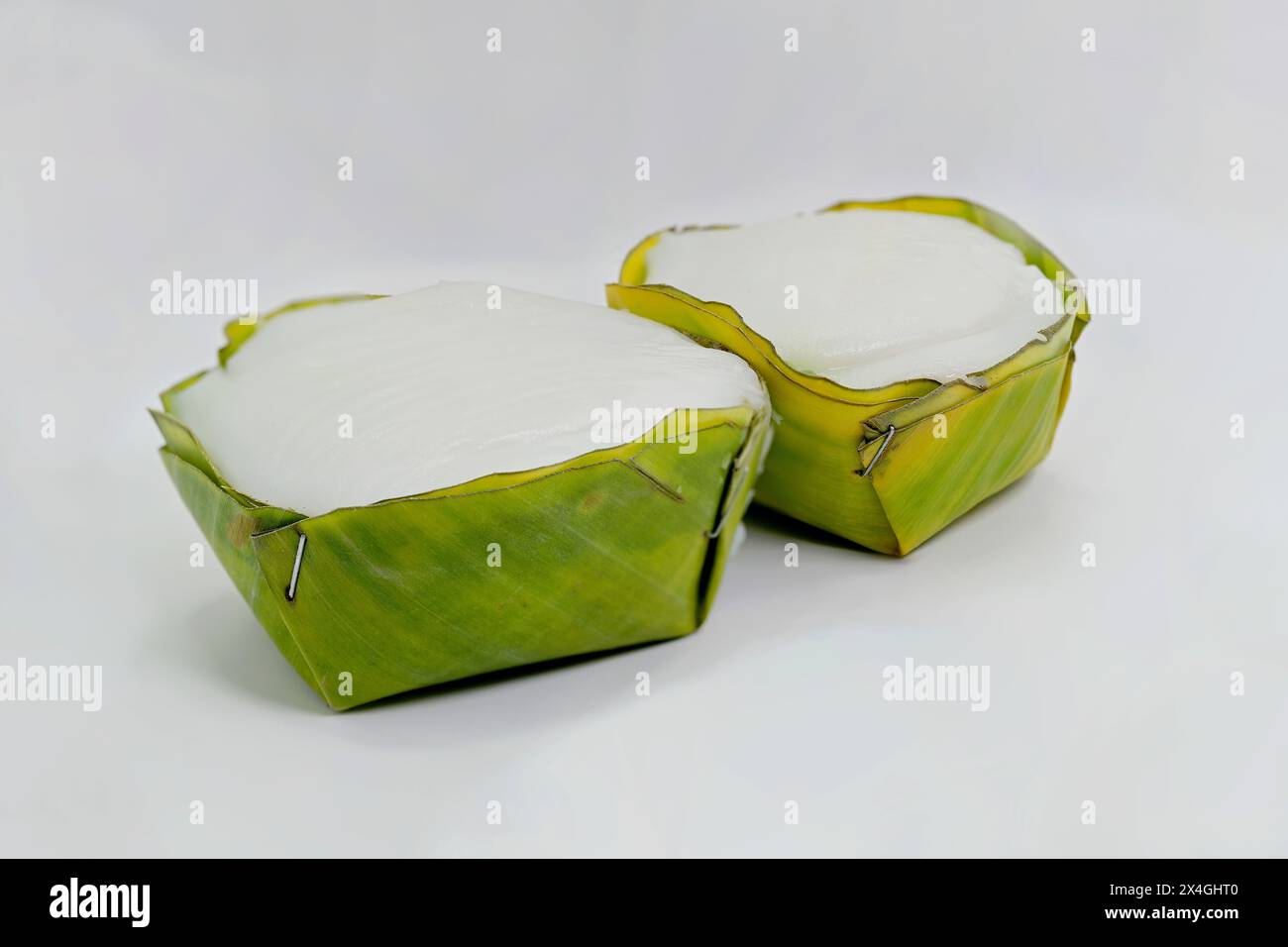 Two Khanom Tako Thai layered coconut pudding desserts, in folded pandan ...