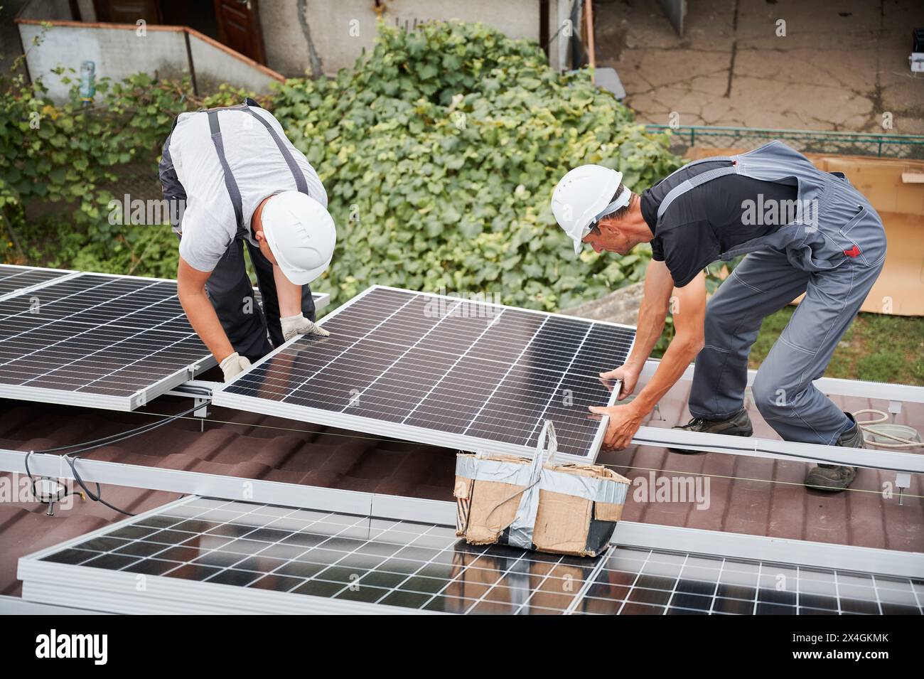 Men technicians installing photovoltaic solar moduls on roof of house ...