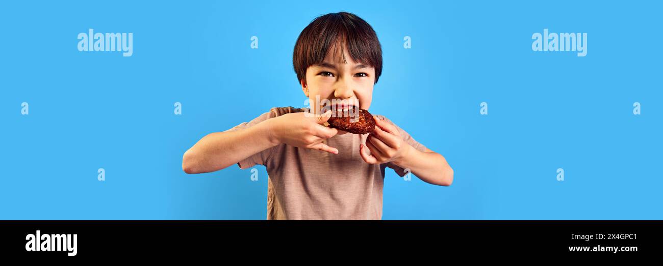 Little boy, child emotionally biting fried meat, cutlet from burger ...