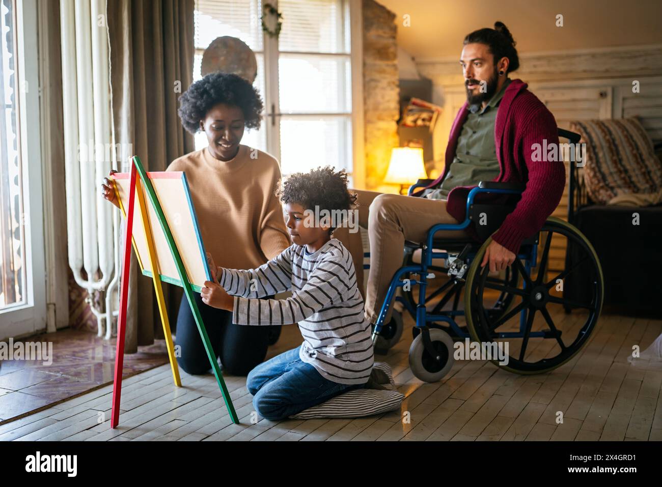 Happy multiethnic family with disability. Father in wheelchair enjoying ...