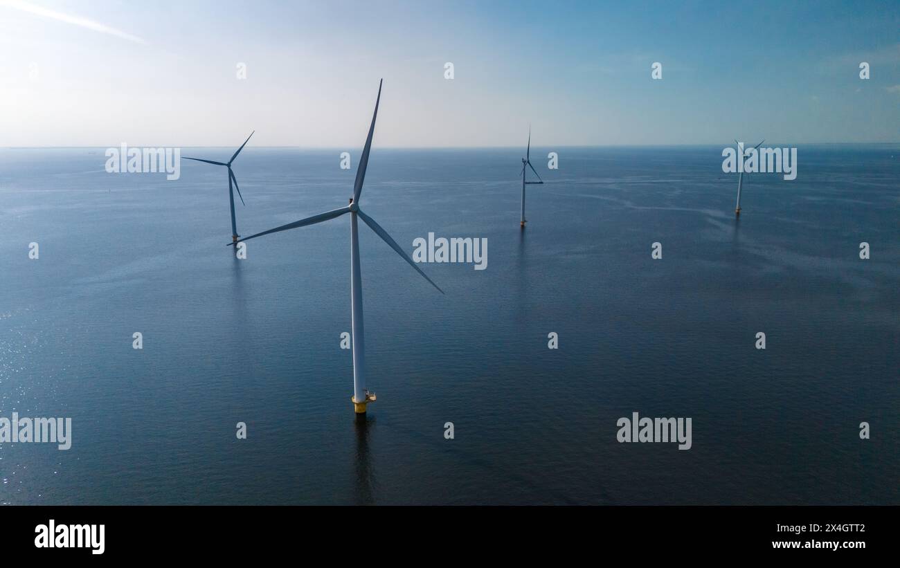 A group of wind turbines stand tall, floating gracefully in the ocean ...