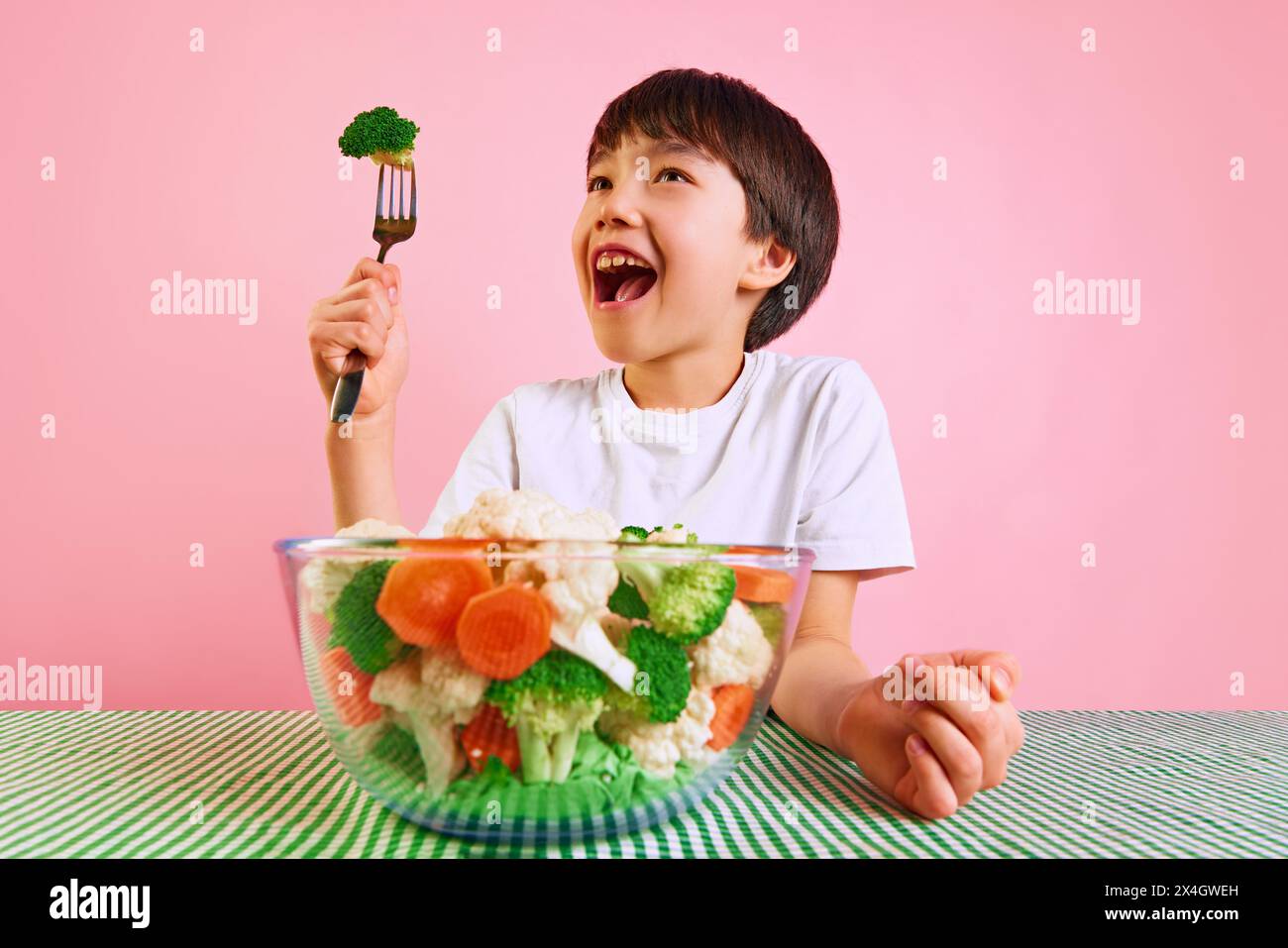 Playful and healthy. Smiling boy, kid raising for with broccoli ...