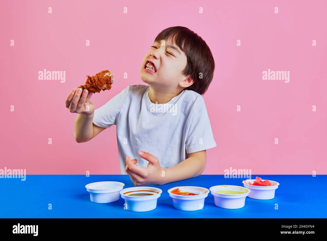 Little boy, Korean kid sitting at table and emotionally eating fried ...