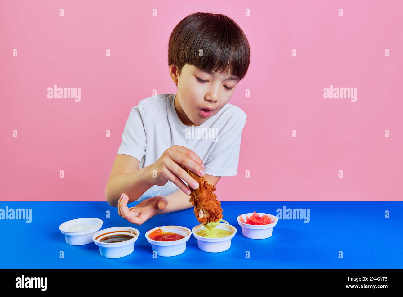 Little boy, Korean kid sitting at table and eating fried chicken ...