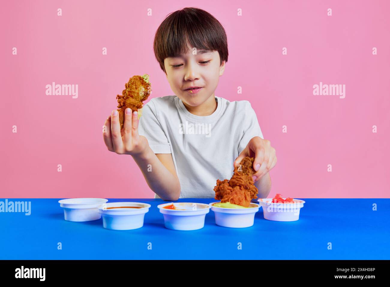 Little boy, Korean kid sitting at table and eating fried chicken ...