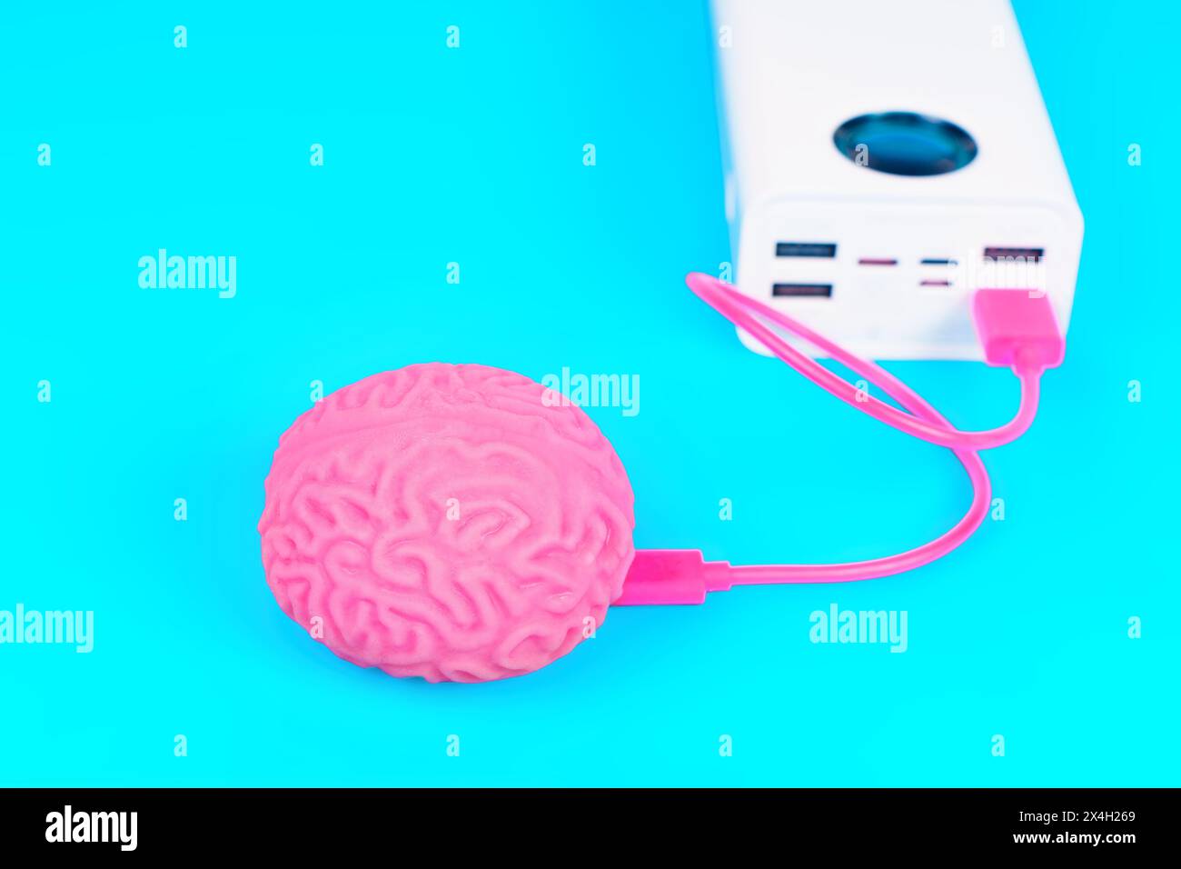 Close-up of a pink human brain model connected to a portable power bank ...