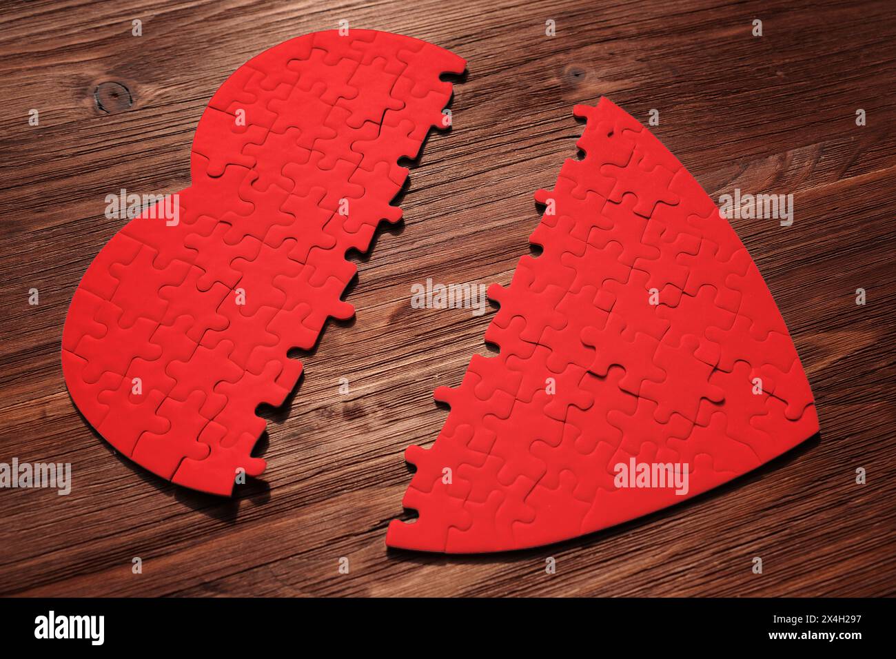 Split red heart jigsaw puzzle, zoomed in, on a dark wooden table ...