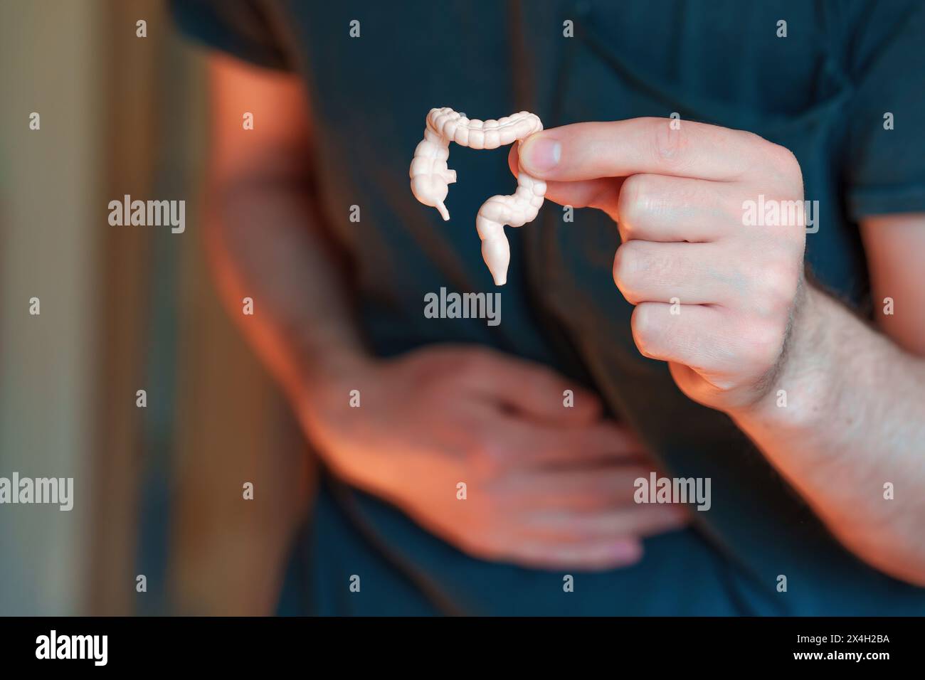 Man hunched over in pain, clutching his stomach with one hand, holding ...