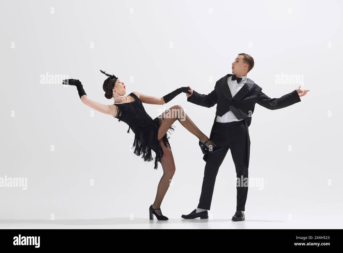 Stylish couple reenacts 1920s dance, woman in fringe dress and man in ...